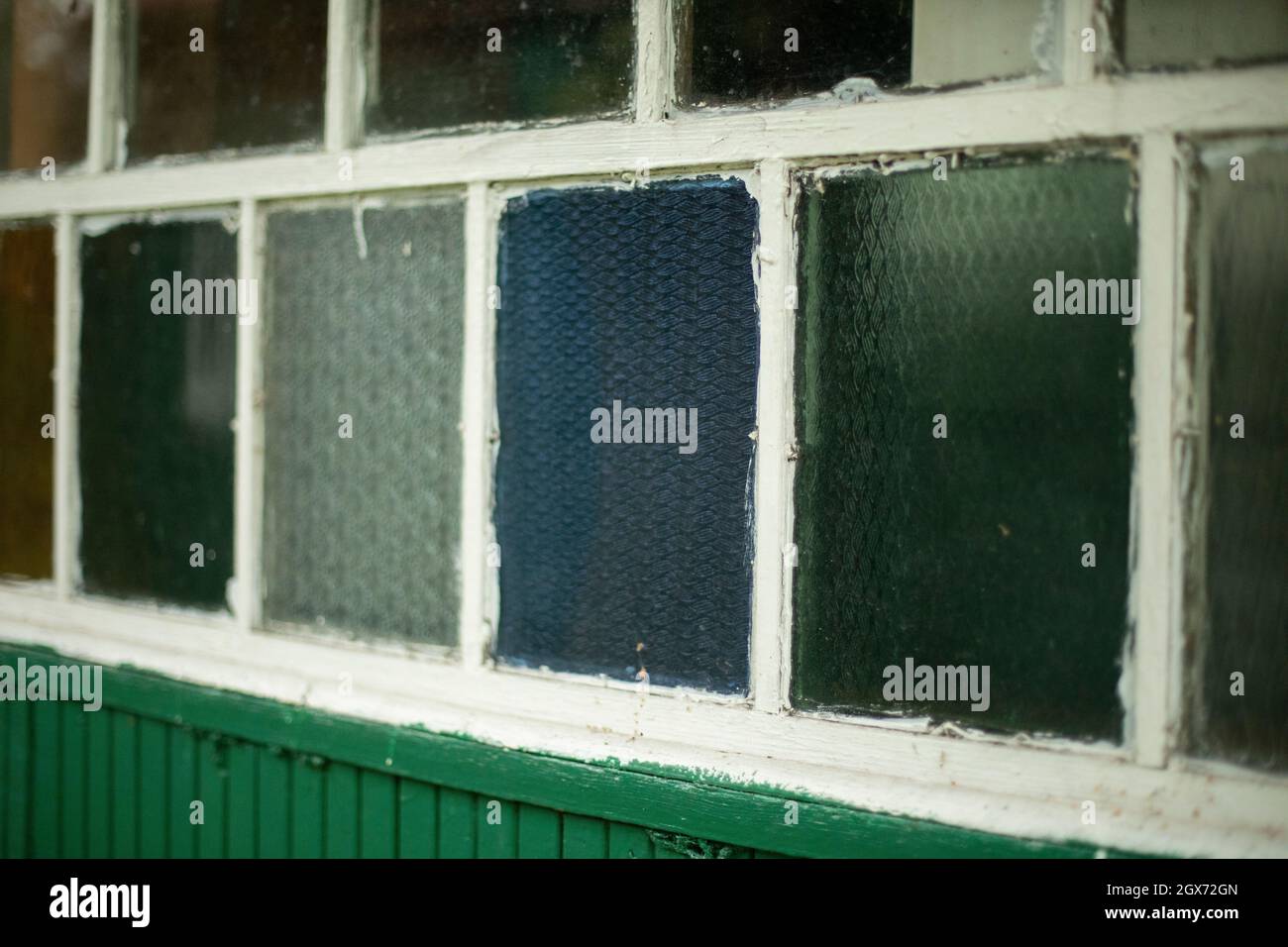 An old window in the village. Colored glass in the window frame. Facade ...