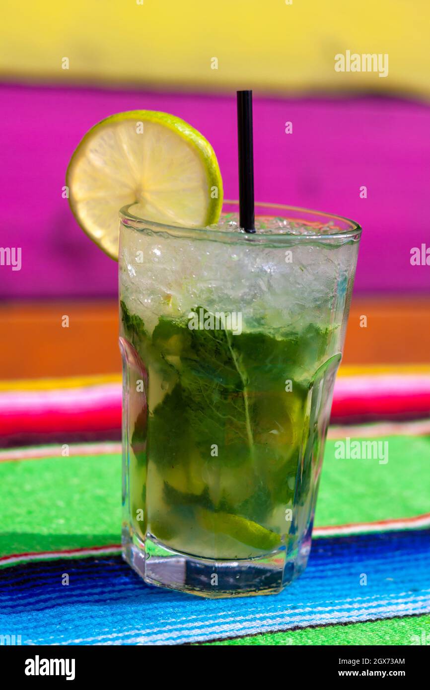 Glass of mochito cocktail on a colored towel with black straw ice and ...