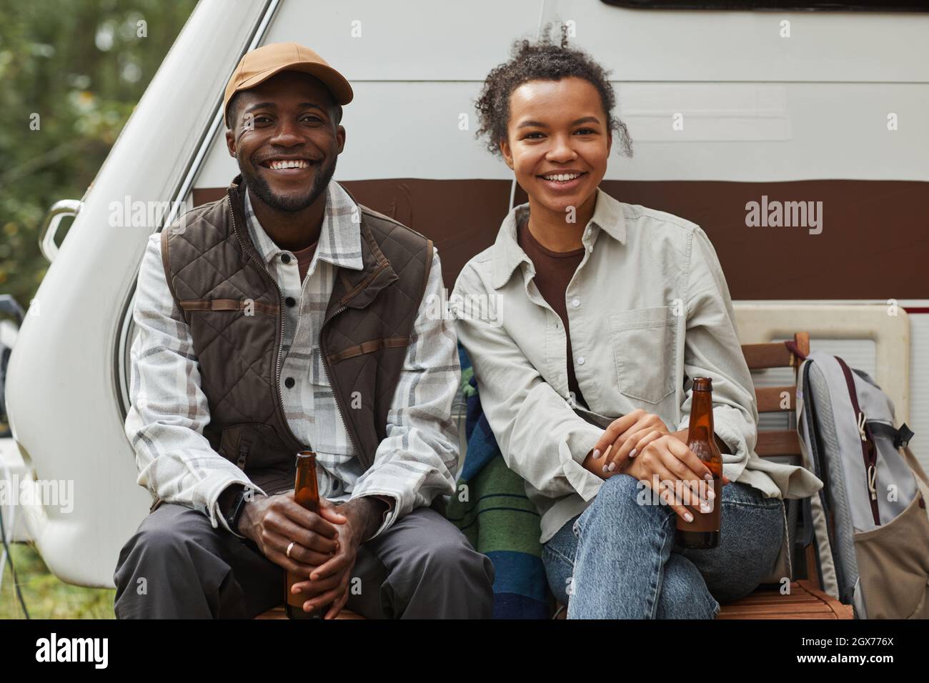 Portrait of young African-American couple relaxing outdoors while ...