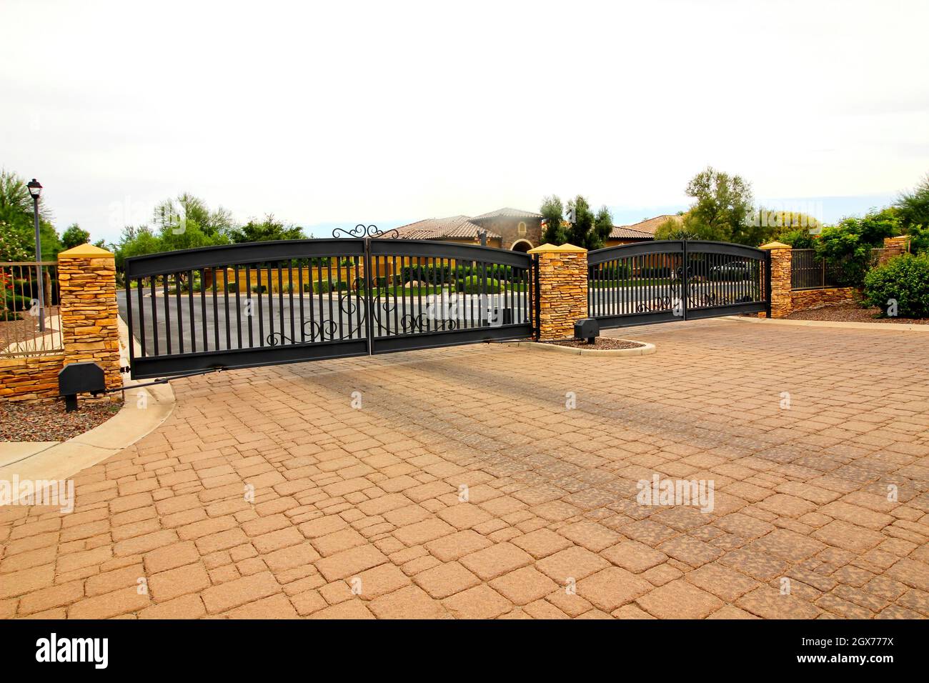 Two Iron Entry And Exit Electric Gates With Pavers Driveway Stock Photo ...