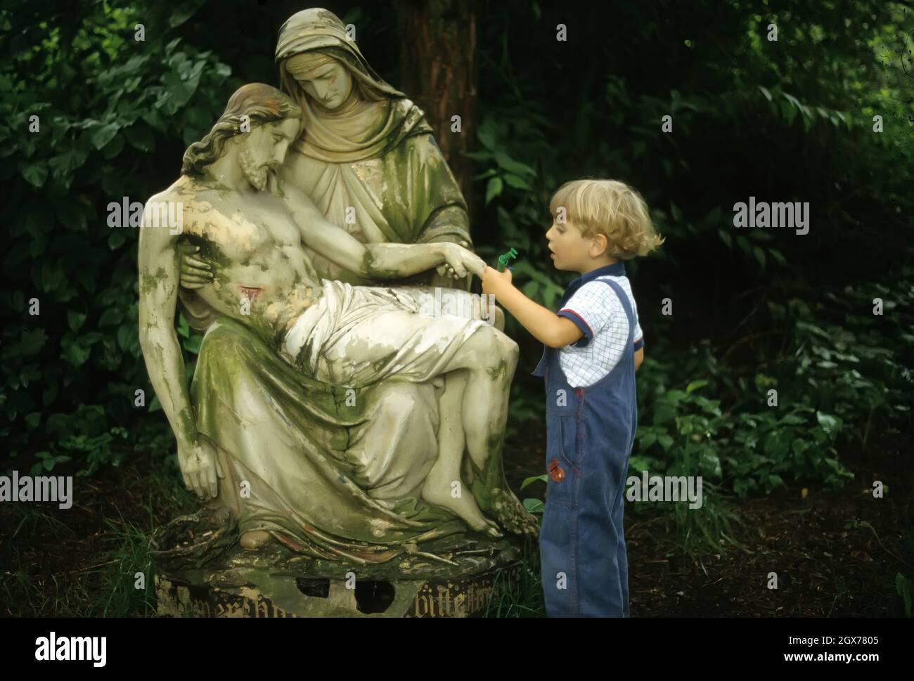 Little boy expressing empathy at at a statue of Jesus and Mary Stock ...
