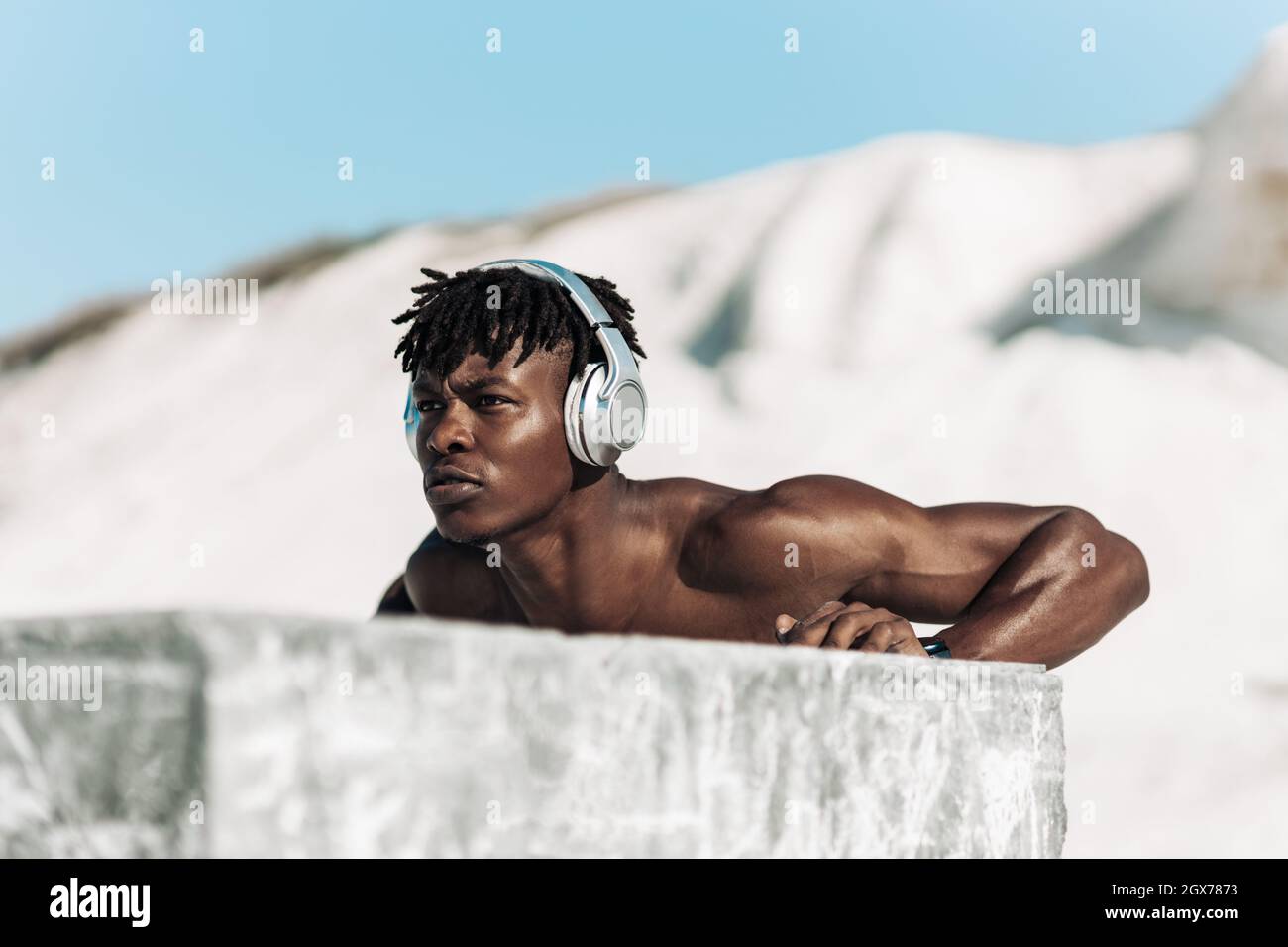 Sporty african black man, wearing wireless headphones, doing push-ups ...