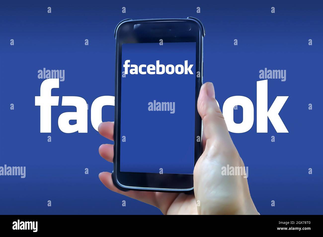 A Human hand holding a smartphone showing a facebook logo Stock Photo ...