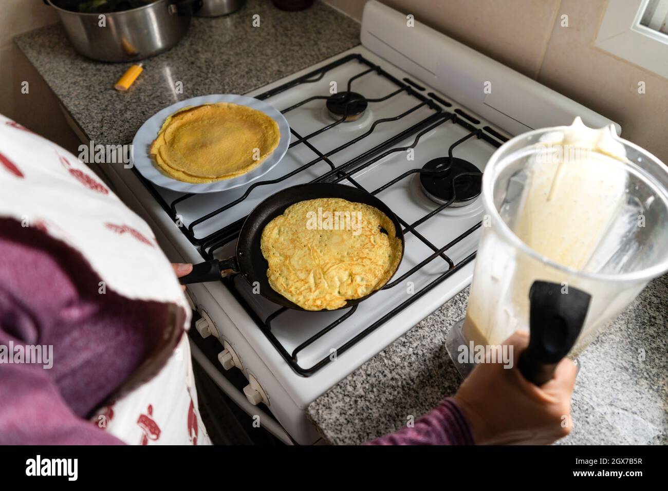 Woman in an apron preparing thin delicious appetizing pancakes in a ...
