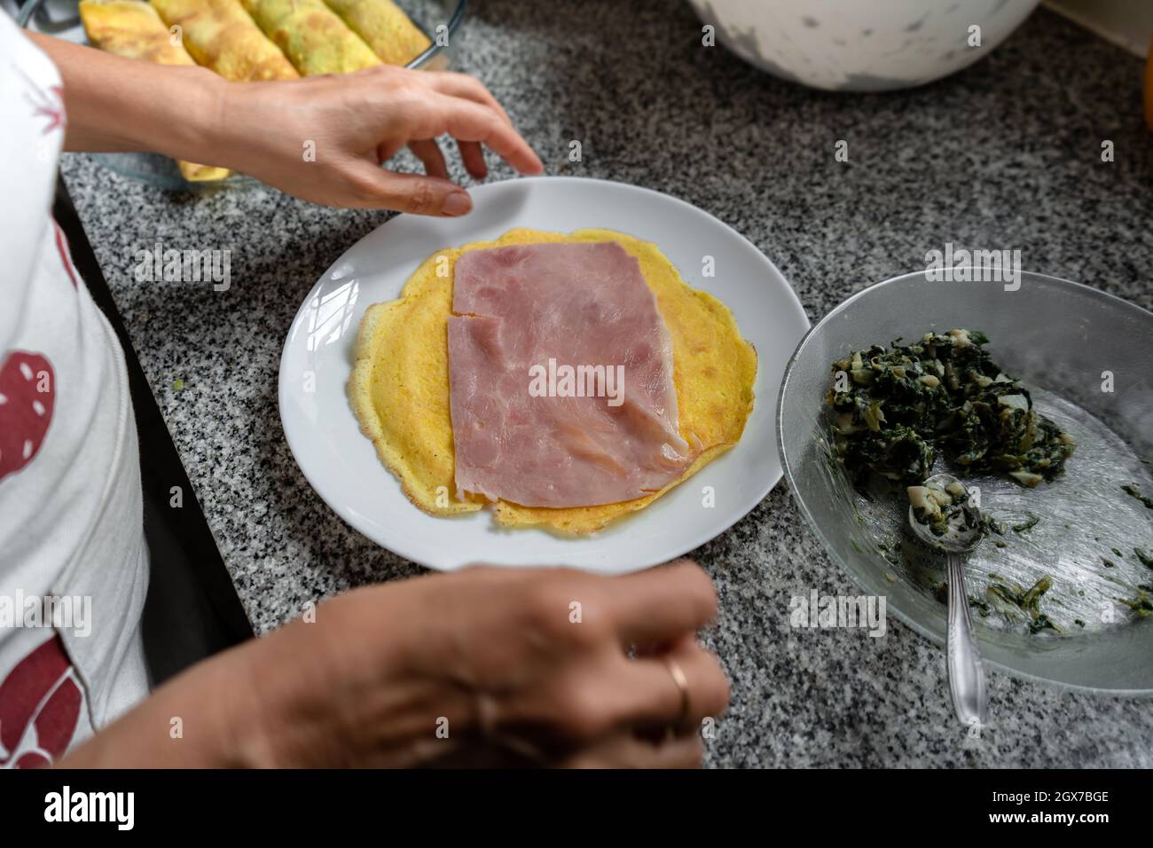 Woman stuffing the thin pancake with spinach filling and ham for ...