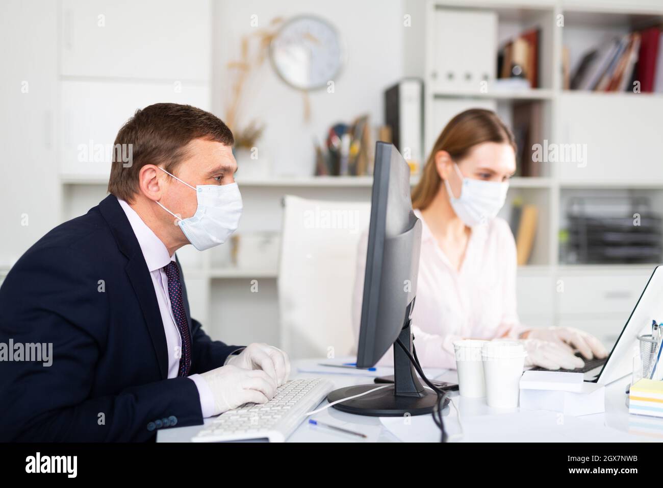 Entrepreneur in medical mask working with female coworker in office ...