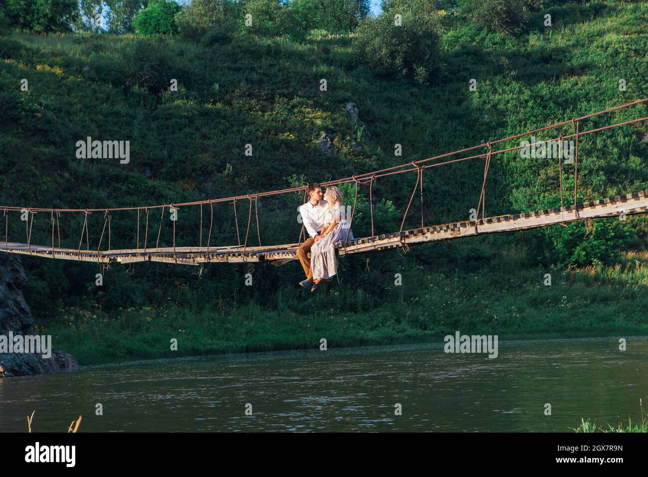 Beautiful young romantic couple sitting and hugging on the suspension ...