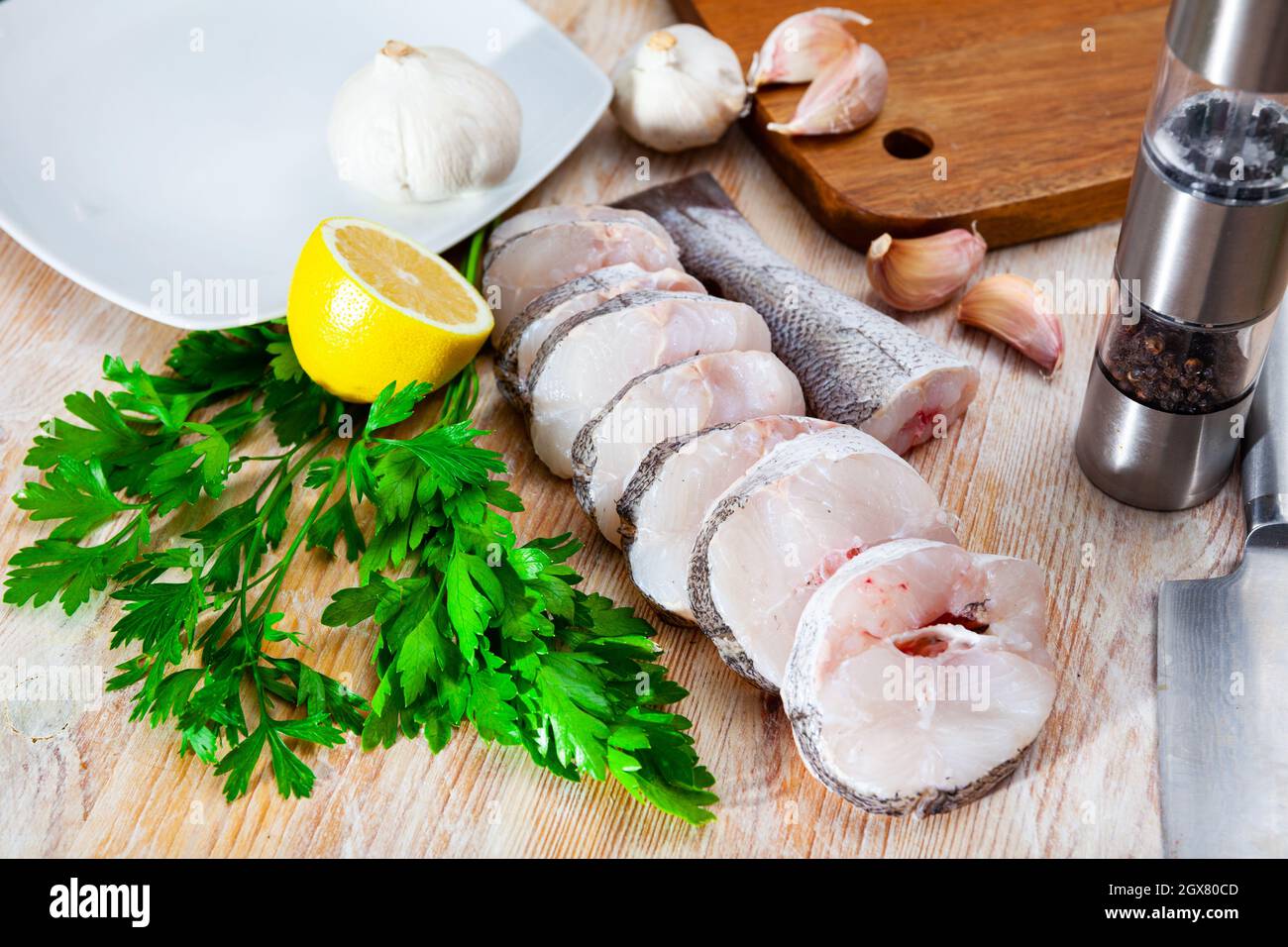 Sliced fresh raw hake with greens, lemon and spices Stock Photo - Alamy
