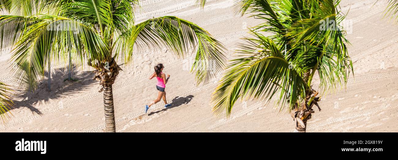 Fitness woman running training on tropical beach in between palm trees ...