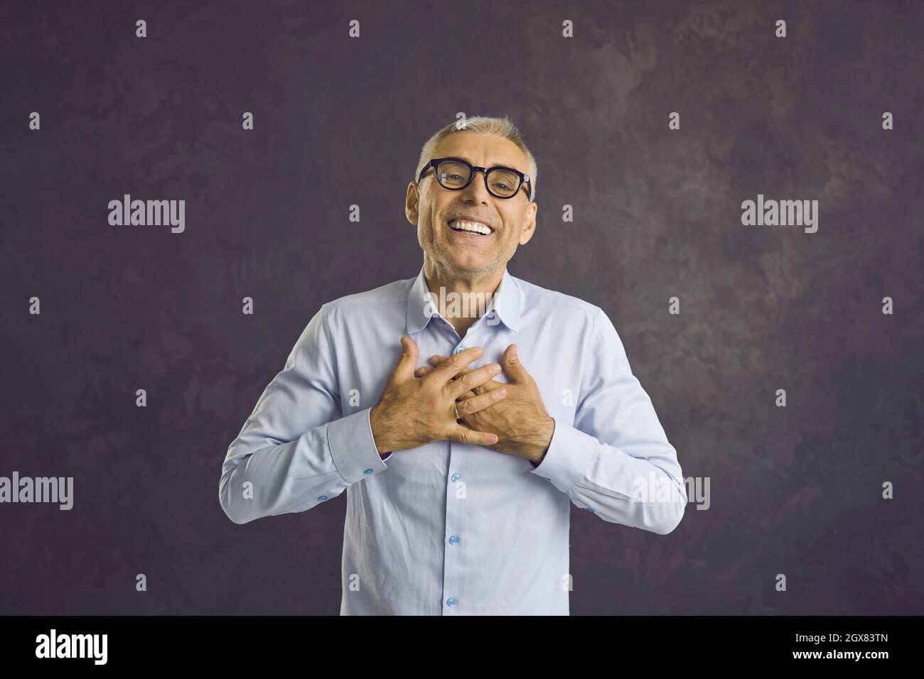 Happy grateful senior man smiling, holding hands on his chest and ...