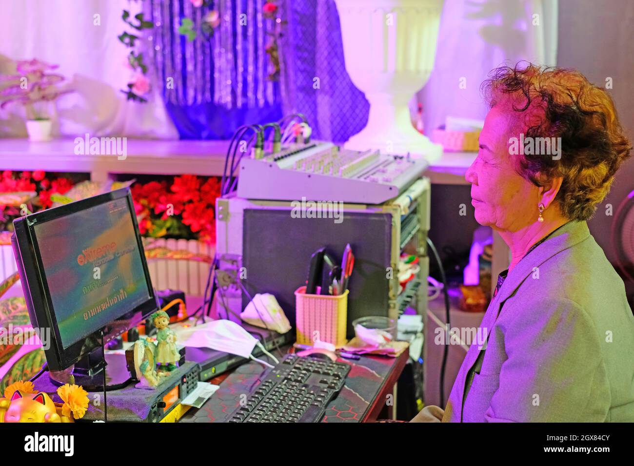 An old woman arranges music audio visual instruments in a Karaoke ...