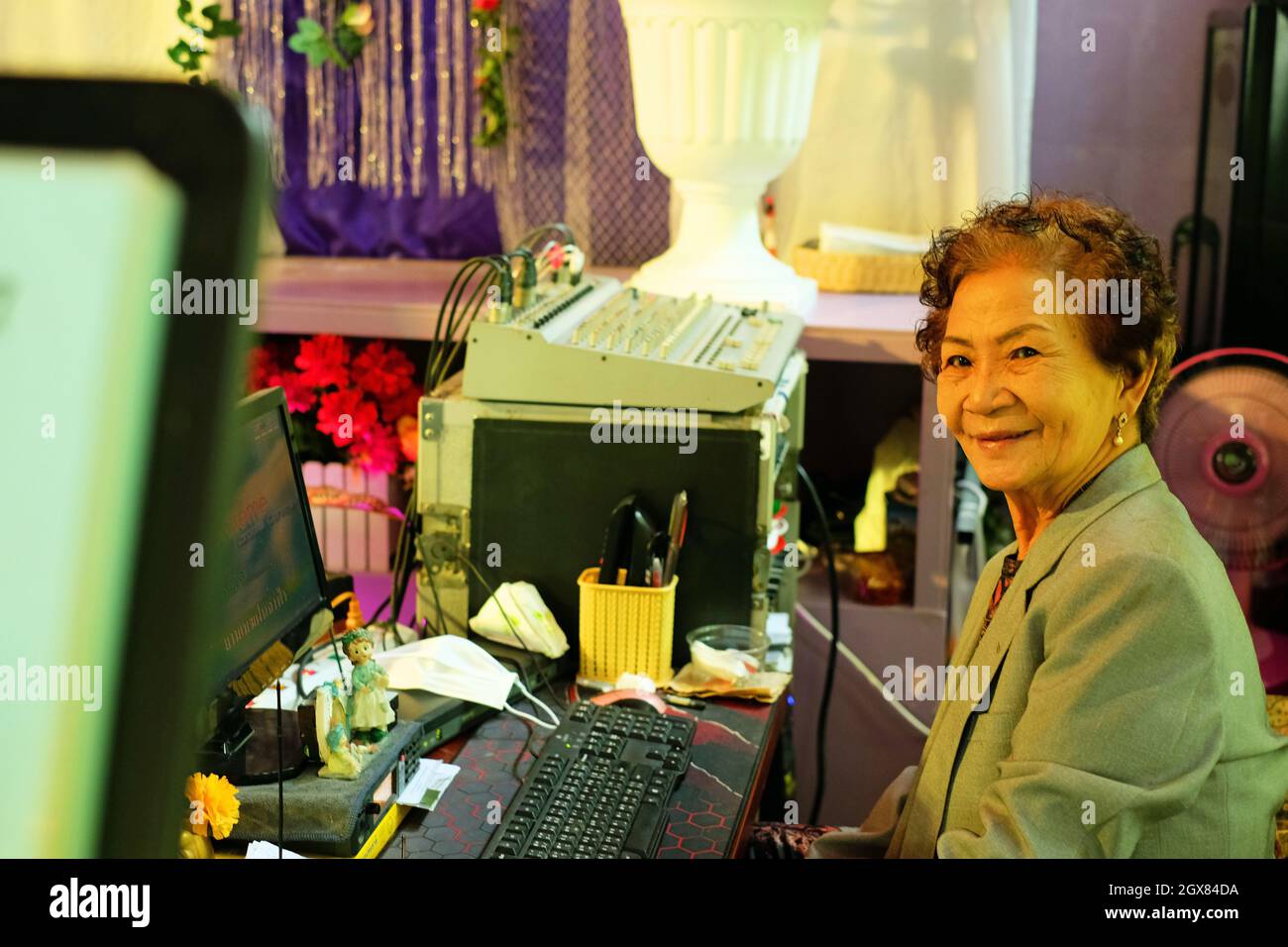 An old woman arranges music audio visual instruments in a Karaoke ...