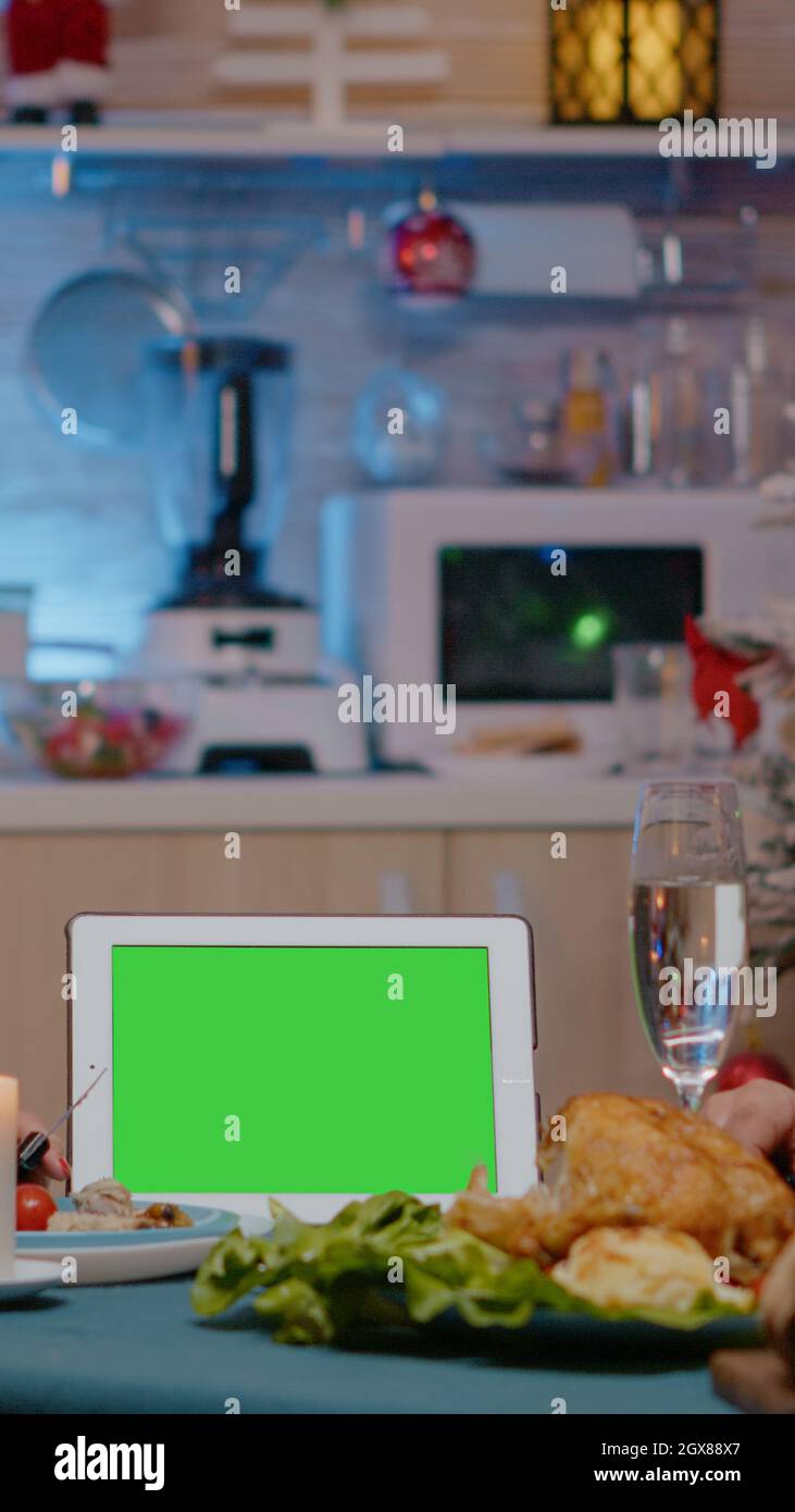 Couple looking at horizontal green screen on tablet while eating meal ...