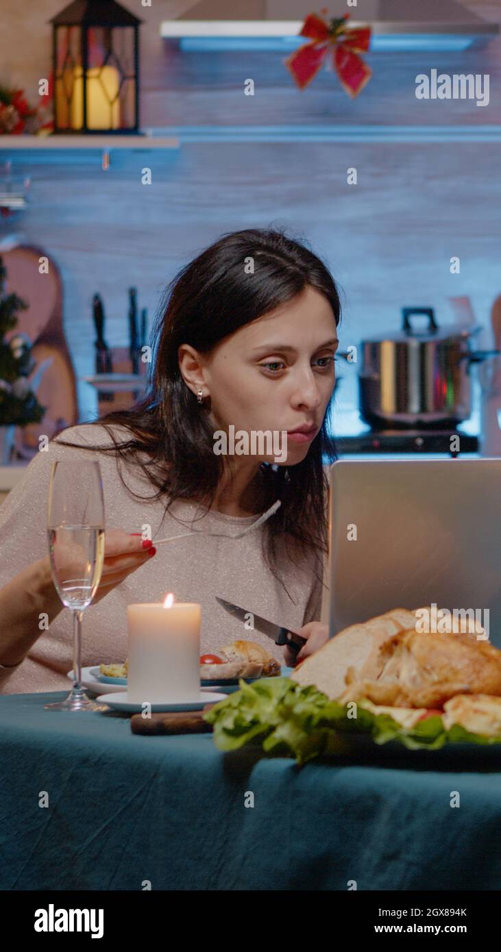 Couple looking at laptop and eating festive meal at christmas eve ...