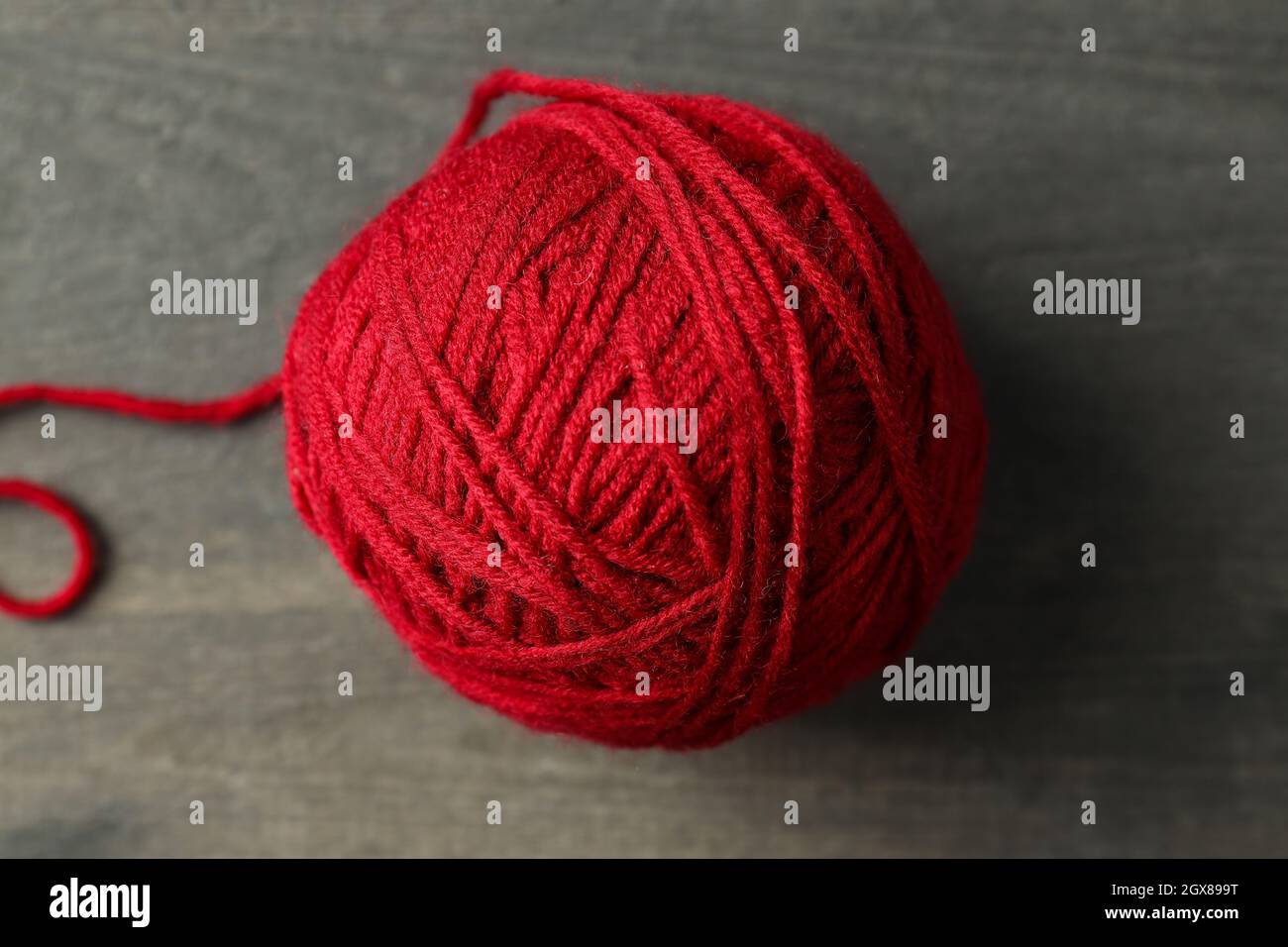Red ball of yarn on gray wooden background Stock Photo - Alamy