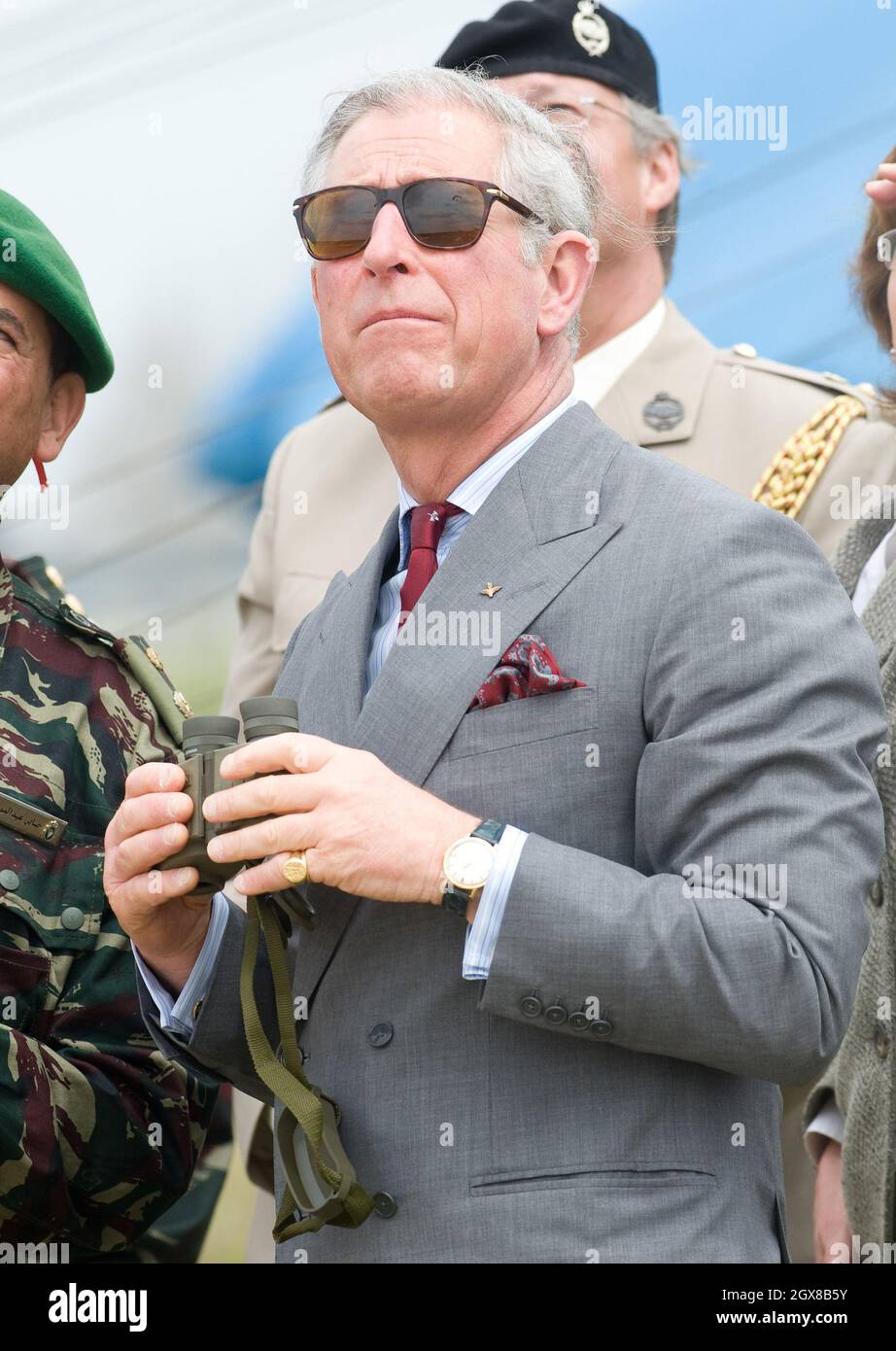 Prince Charles, Prince of Wales watches a display through binoculars ...