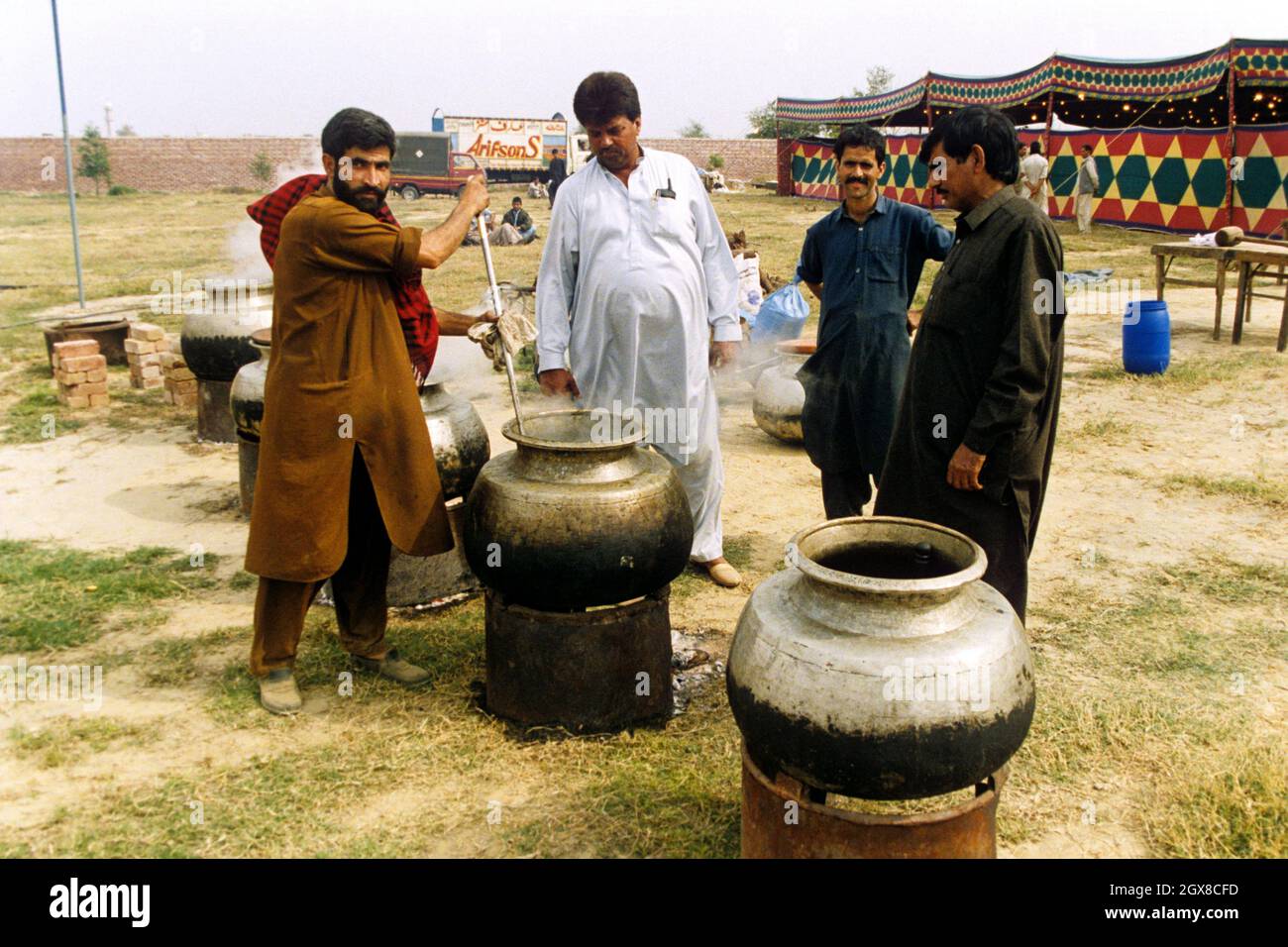 Pakistanis stirring a large pot during a visit to Pakistan by the ...