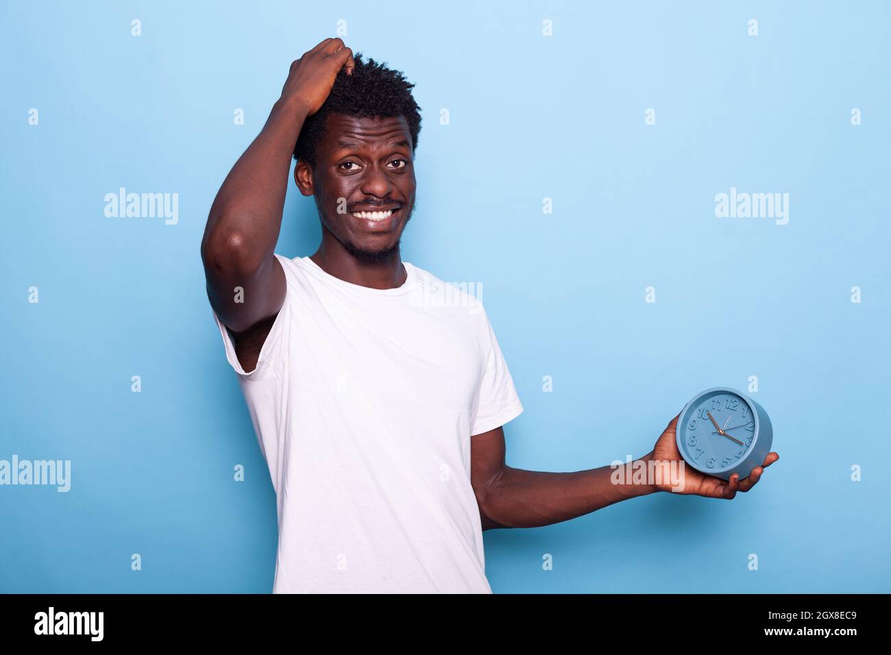 Portrait of man with wall clock holding hand on head, running late to ...