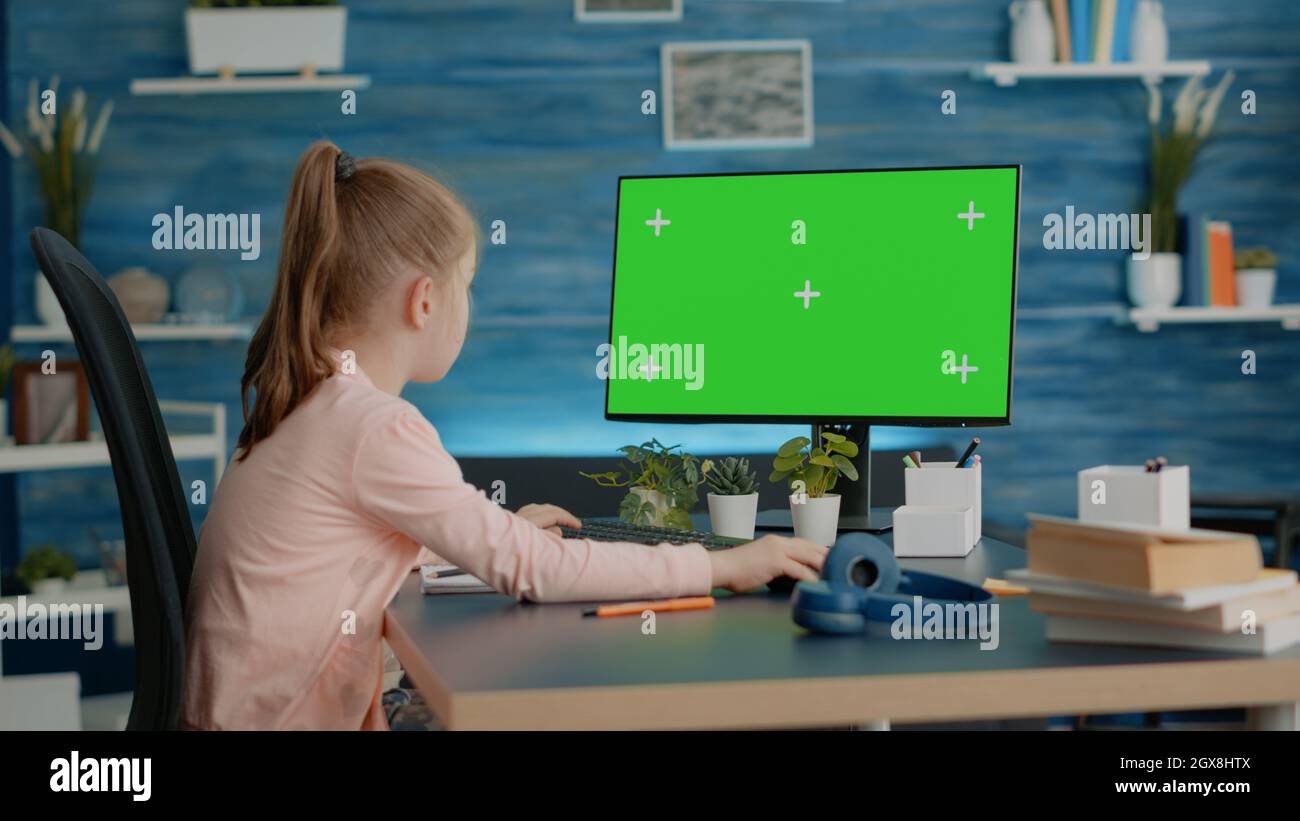Schoolgirl looking at computer with horizontal green screen at home for ...