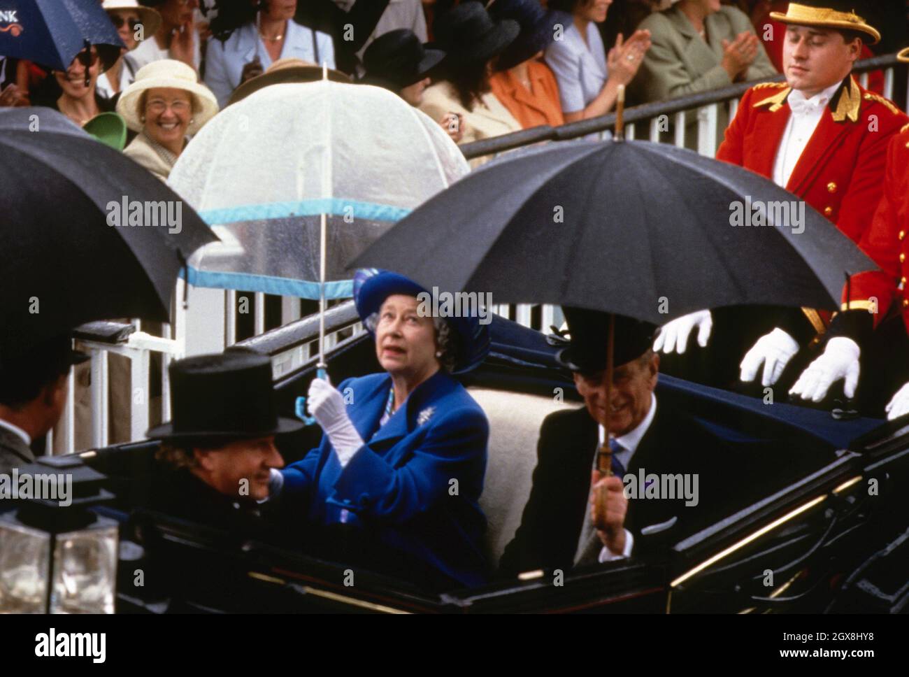 The Queen and the Duke of Edinburgh cover up against the rain, as they ...