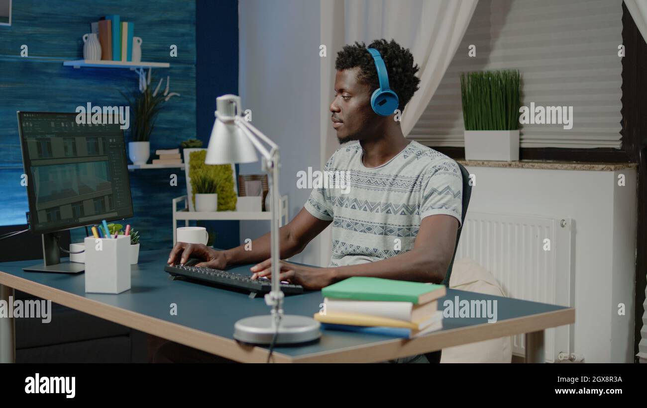 Engineer with headphones creating building model on computer. Architect ...