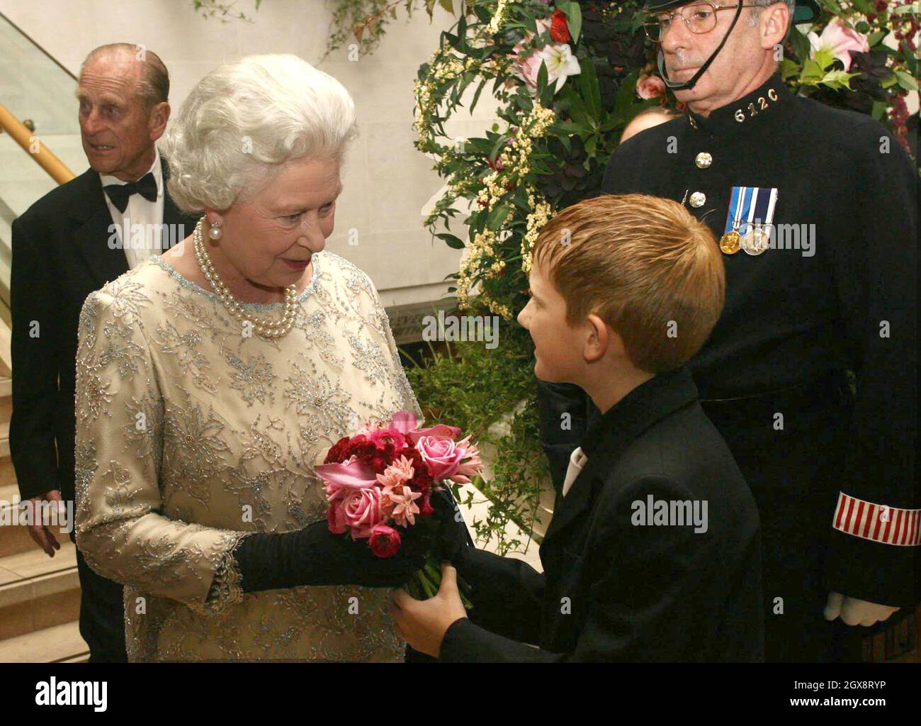 Queen Elizabeth II is presented with a posy by Sam Aston, who plays ...