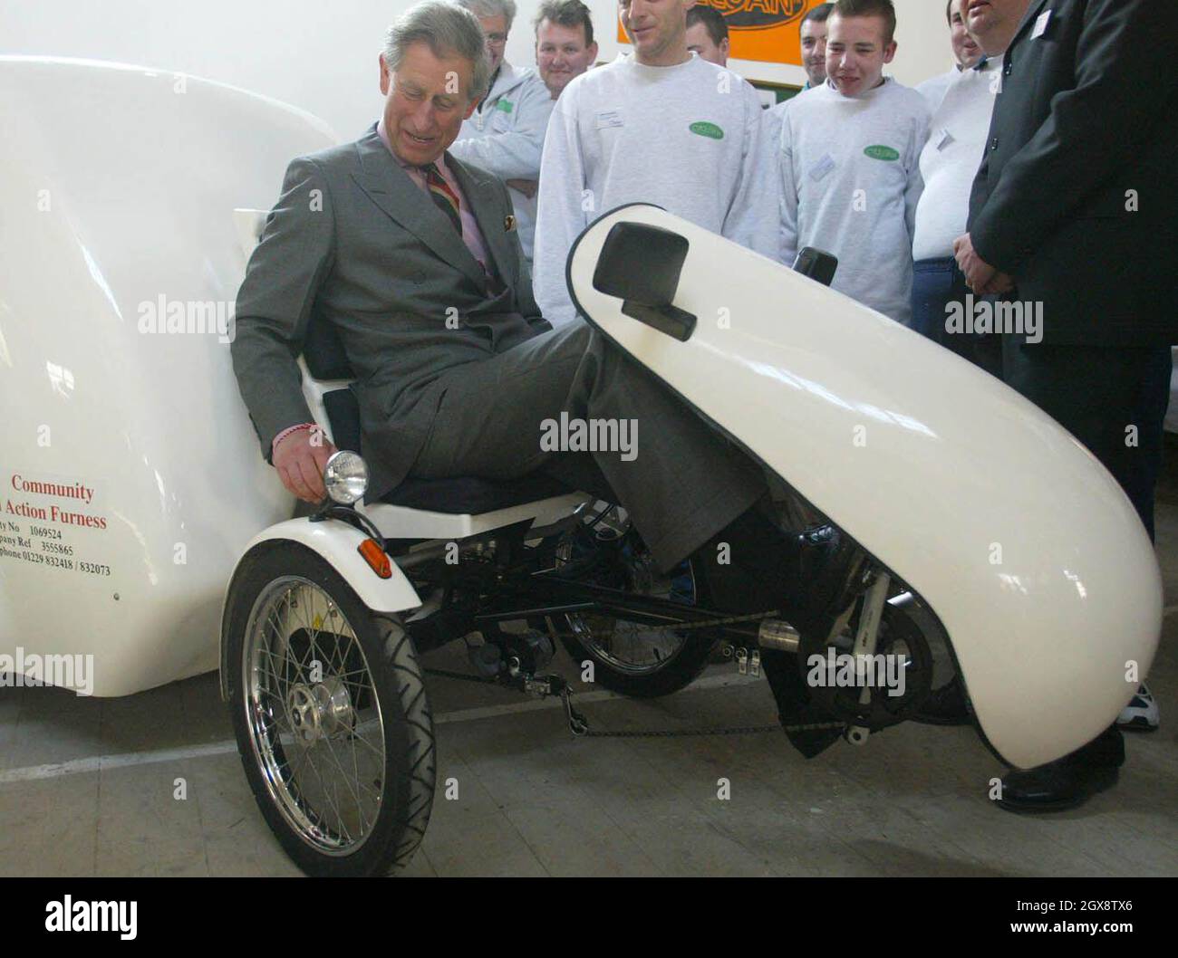 The Prince of Wales sits on a courier cycle during a visit to the ...