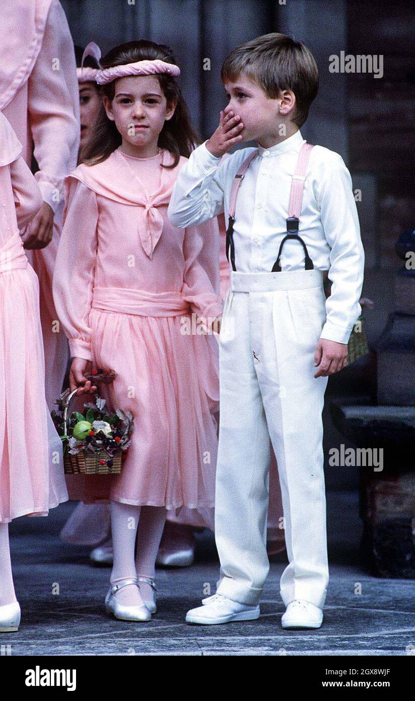 A young Prince William, dressed all in white, at a wedding in ...