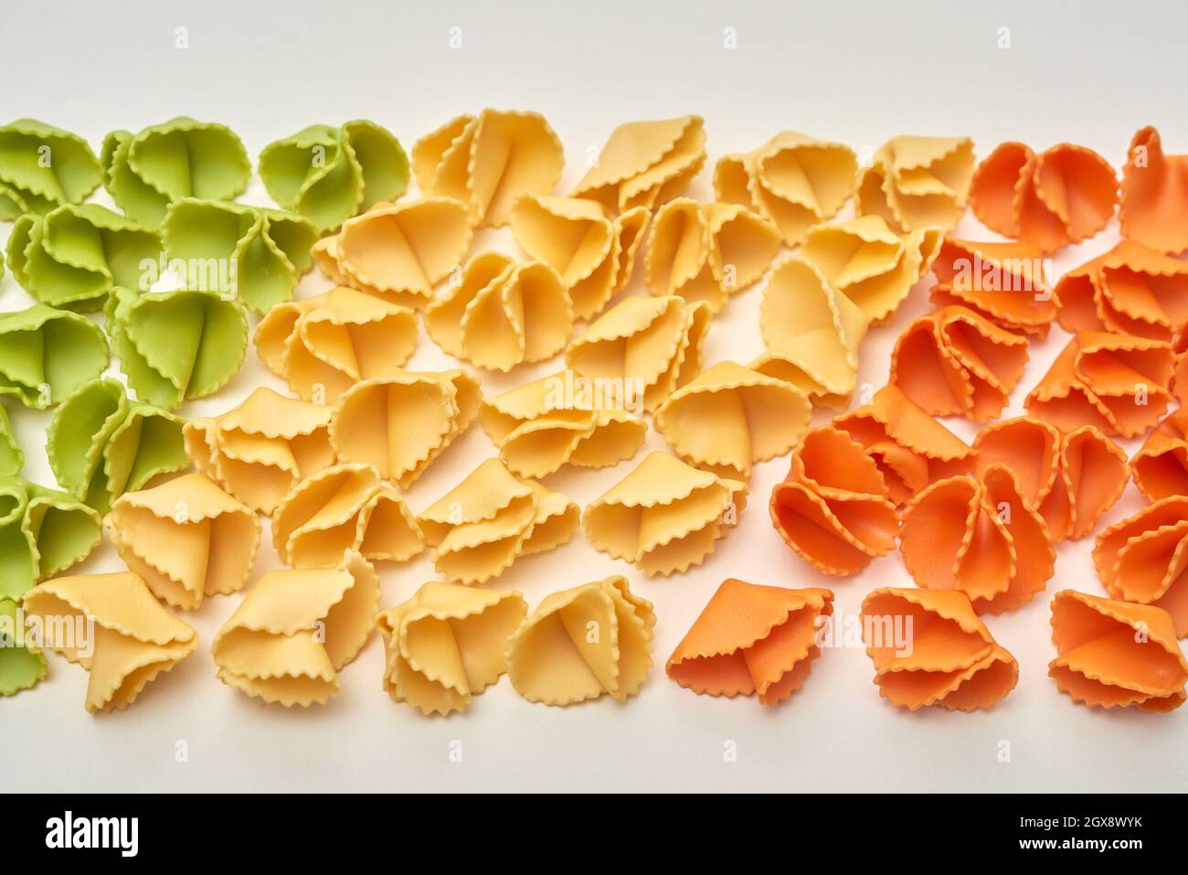 Rows of colorful raw pasta shaped as corners on isolated background ...