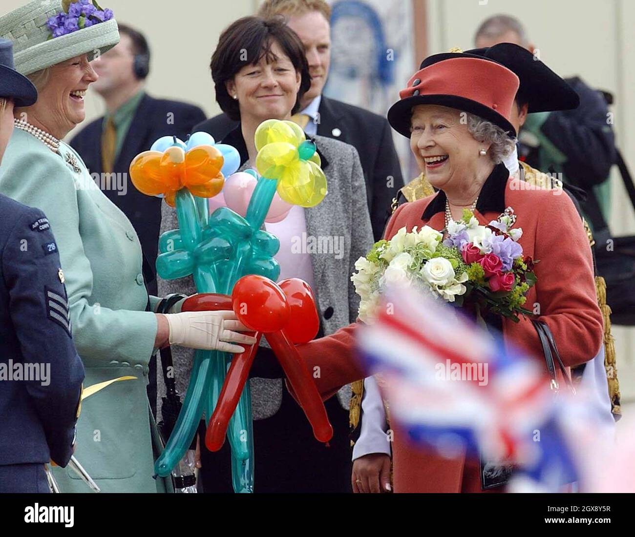 Britain's Queen Elizabeth II hands over a bunch of balloons given to ...