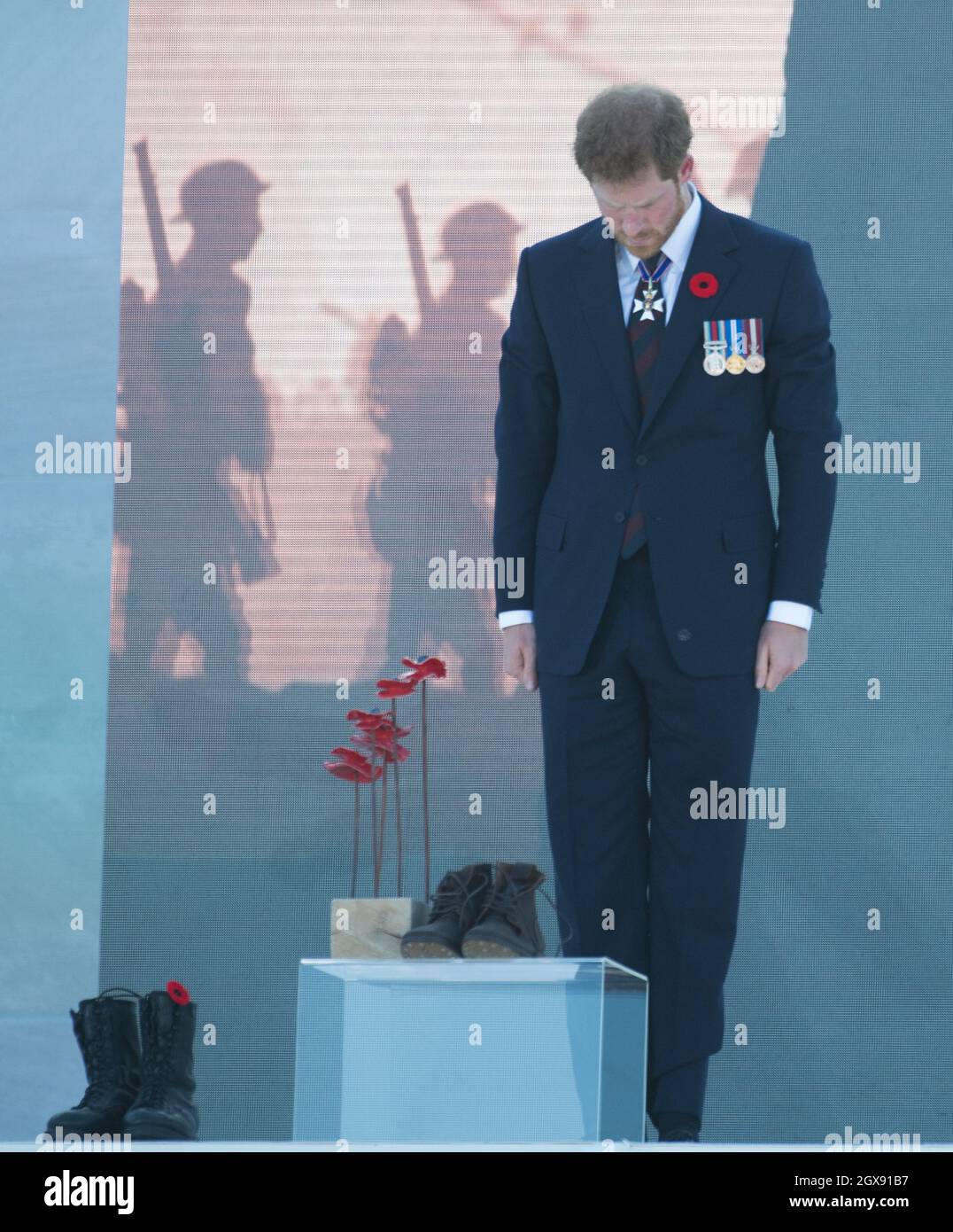 Prince Harry lays down a pair of boots and poppies during the ...
