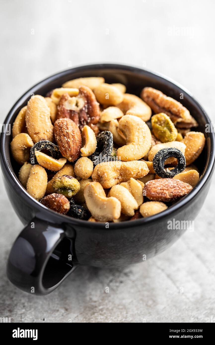 Mix of salted nuts in cup on kitchen table Stock Photo - Alamy