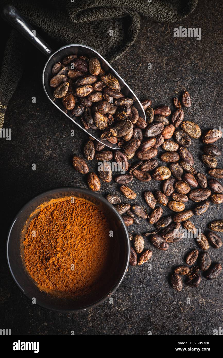 Cocoa powder and cocoa beans in scoop on black table. Top view Stock ...