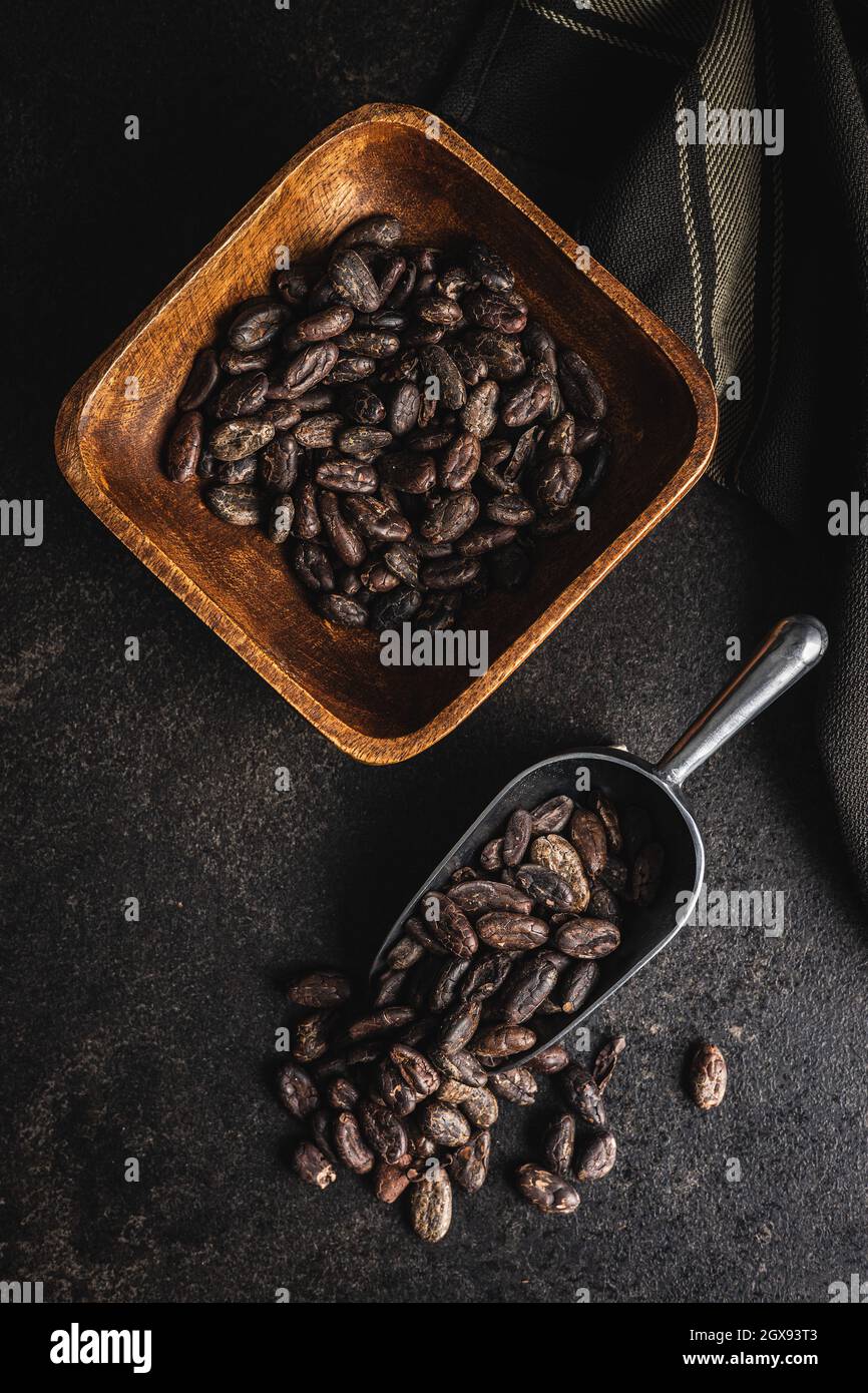 Roasted cocoa beans in scoop on black table. Top view Stock Photo - Alamy