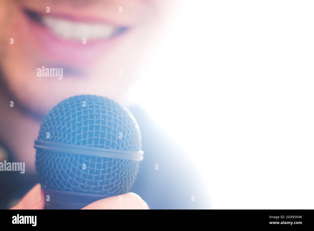 Young man holding a black microphone and speaking into it Stock Photo ...