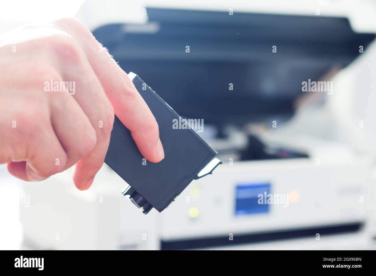 Third party printer cartridge in the hand, printer in the blurry ...