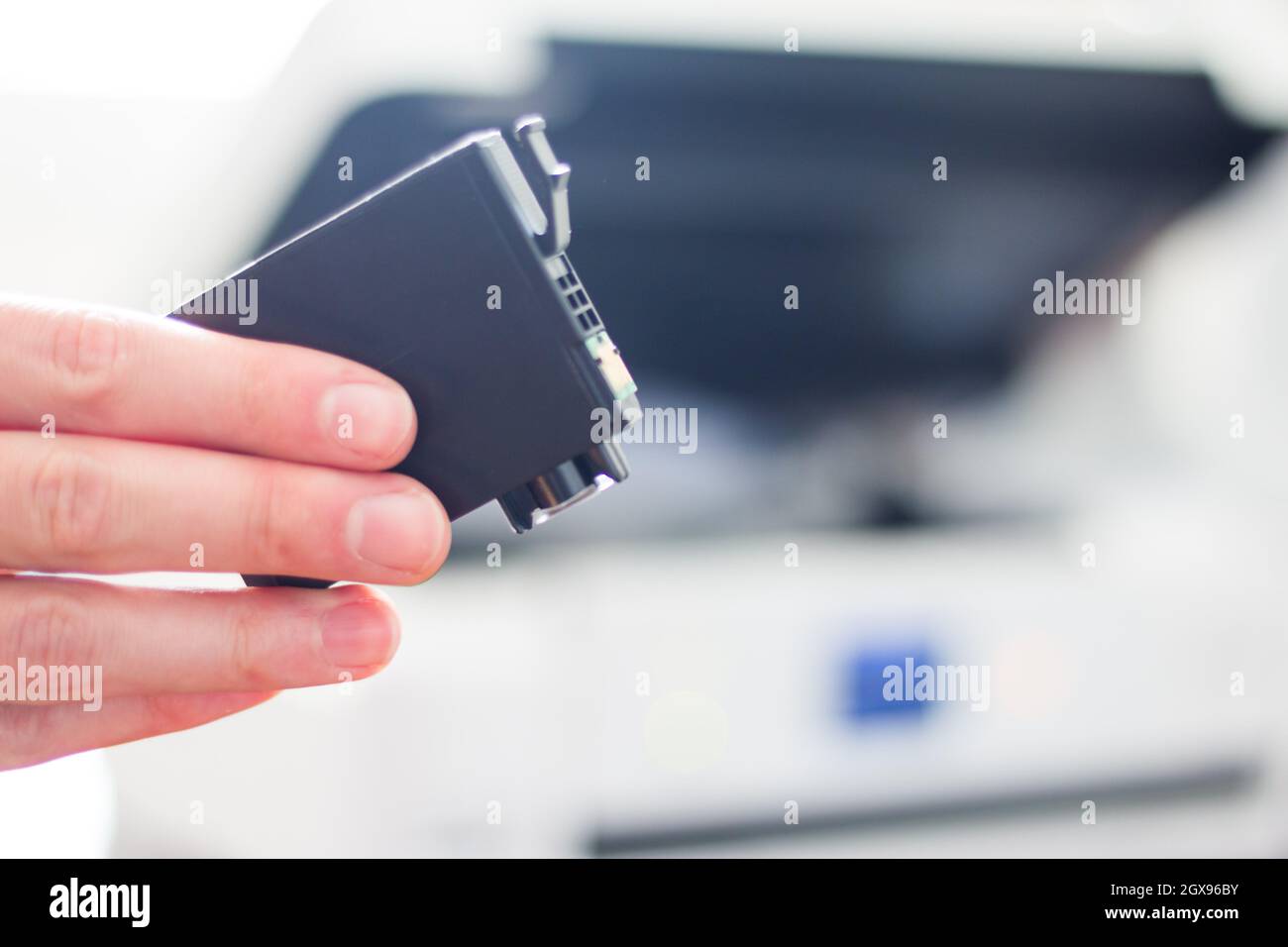 Third party printer cartridge in the hand, printer in the blurry ...