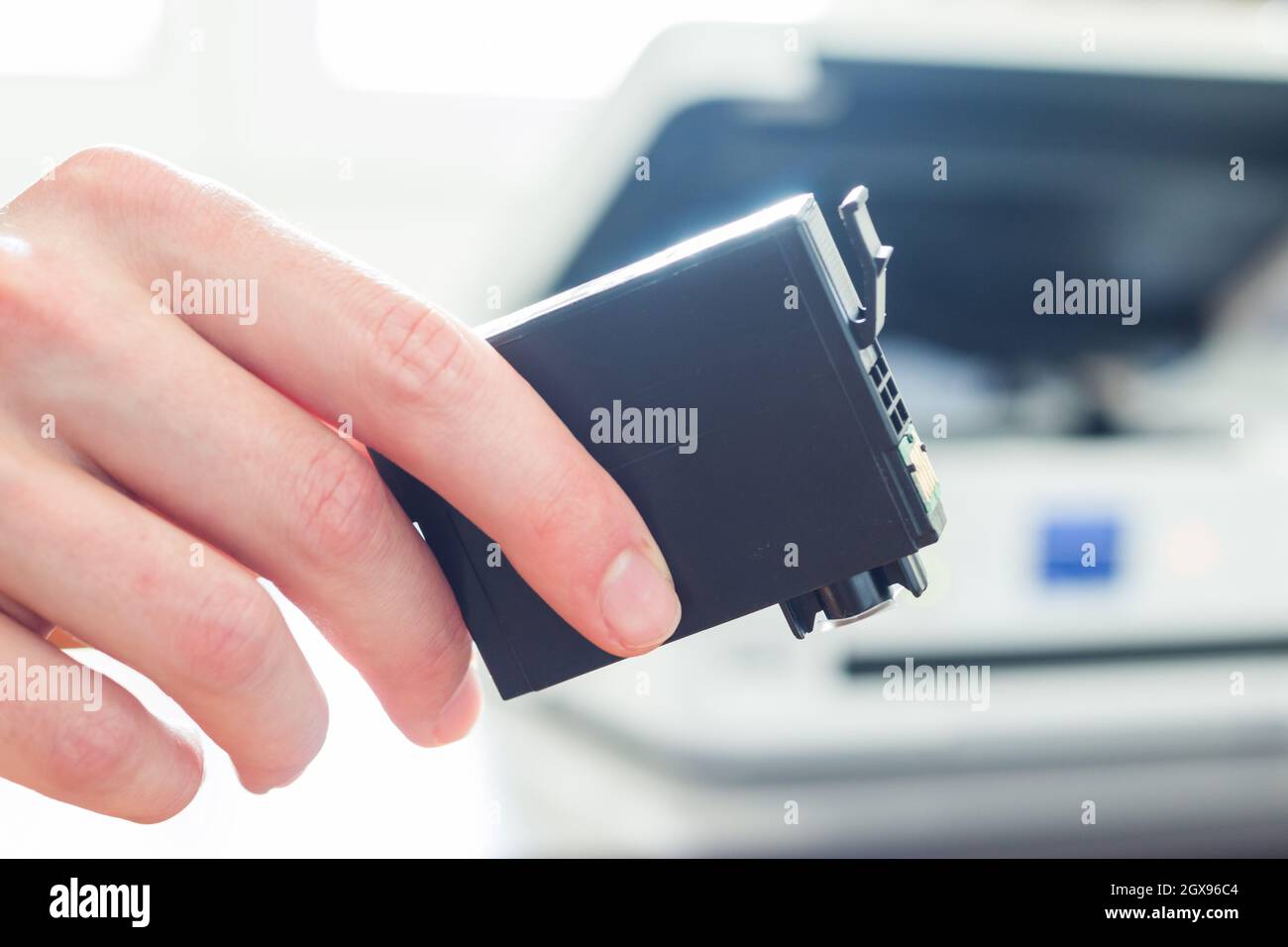 Third party printer cartridge in the hand, printer in the blurry ...
