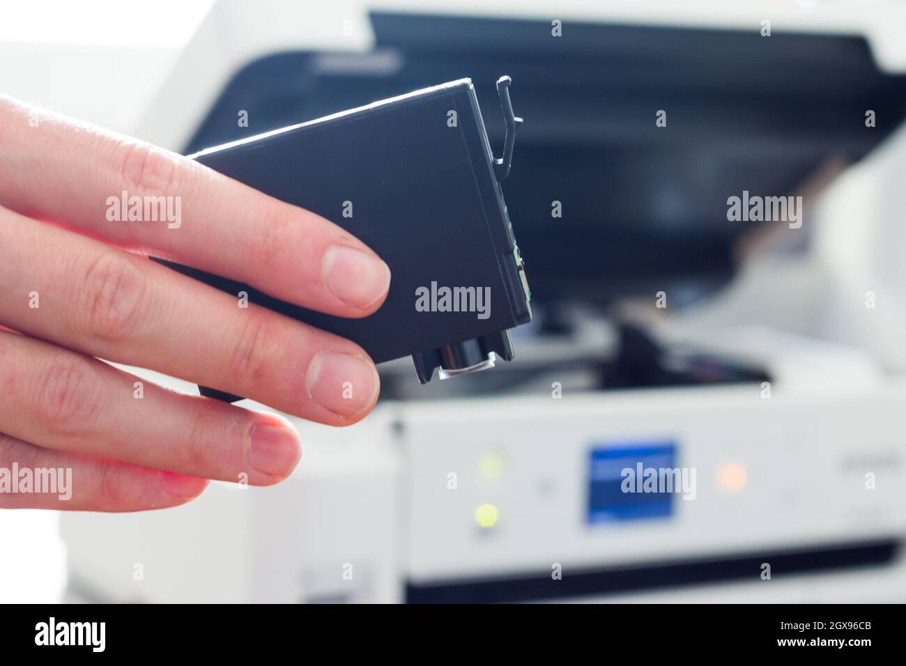 Third party printer cartridge in the hand, printer in the blurry ...