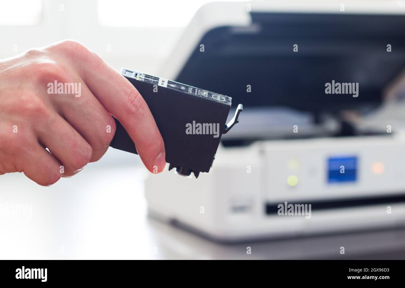 Third party printer cartridge in the hand, printer in the blurry ...