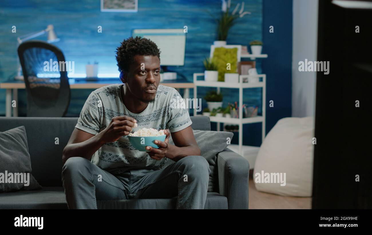 African american man enjoying comedy on television while eating popcorn ...