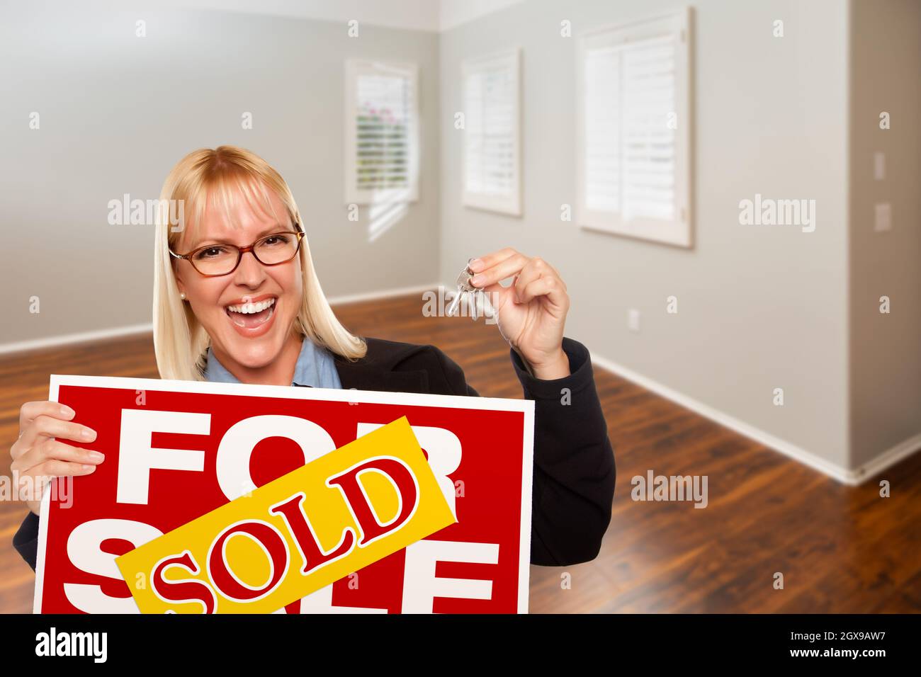 Woman with Sold For Sale Real Estate Sign and Keys In Empty Room of New ...