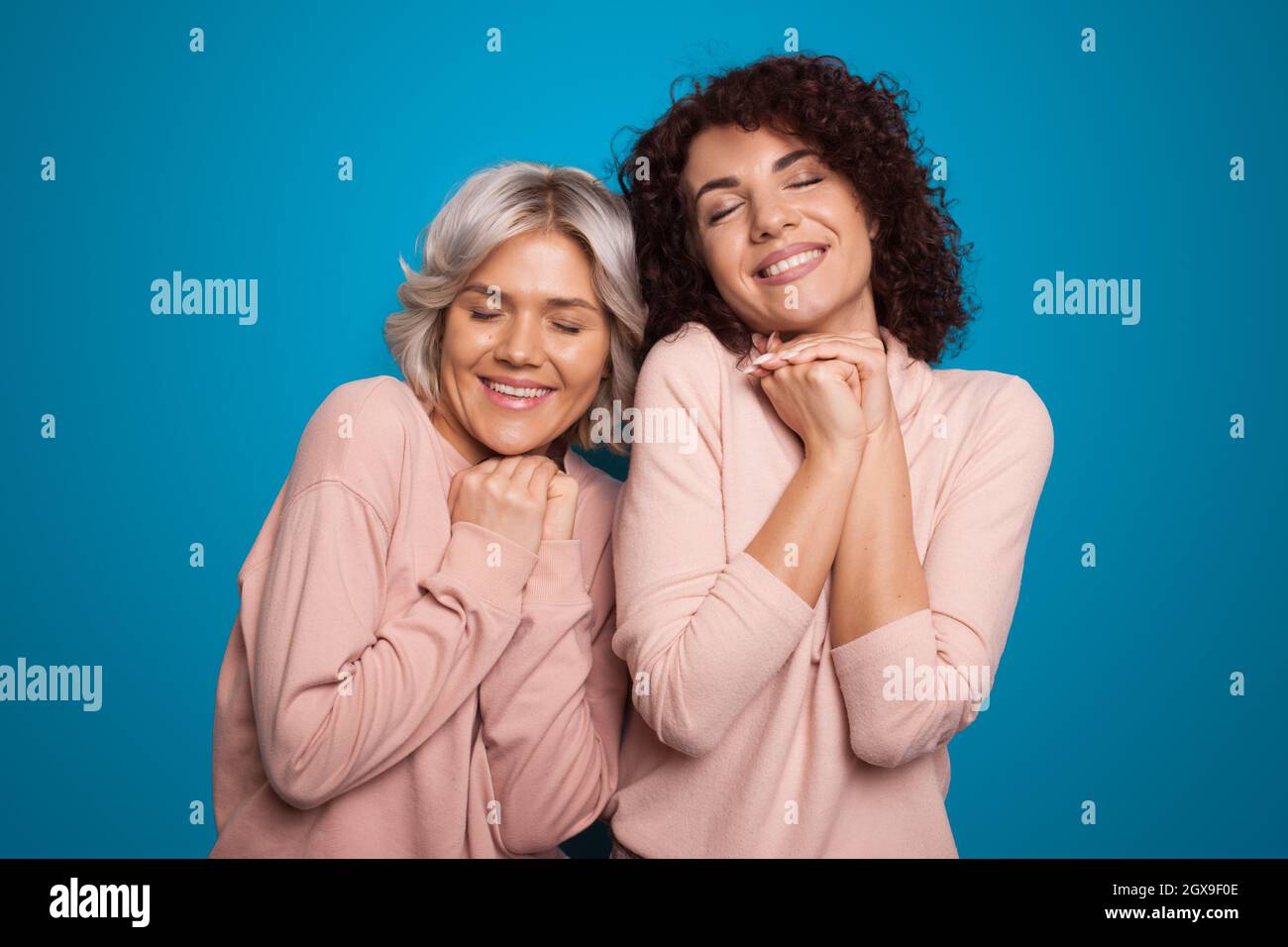 Beautiful portrait of curly sister on studio wall dreaming together ...
