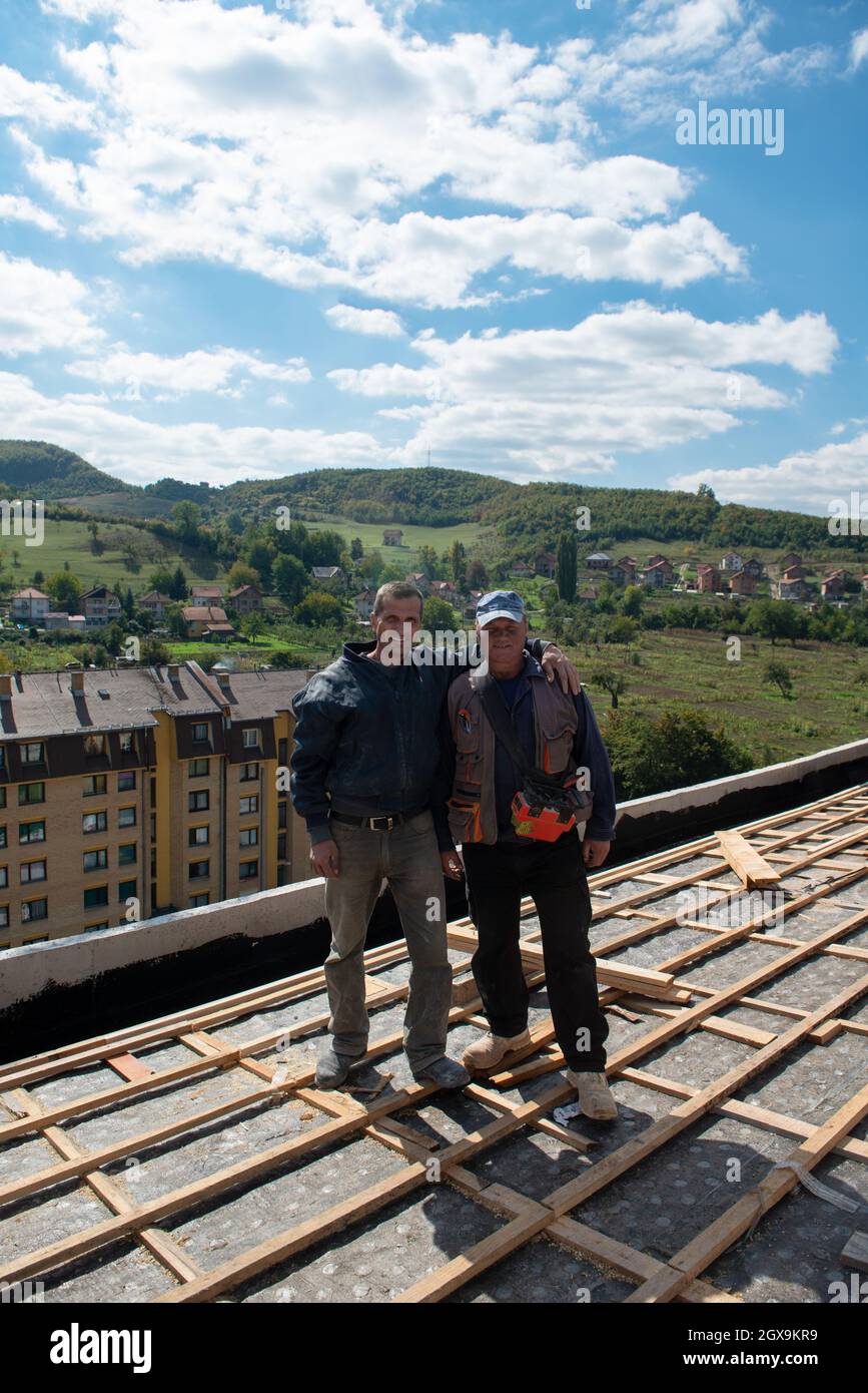 Construction workers working on new roof structure of building on ...