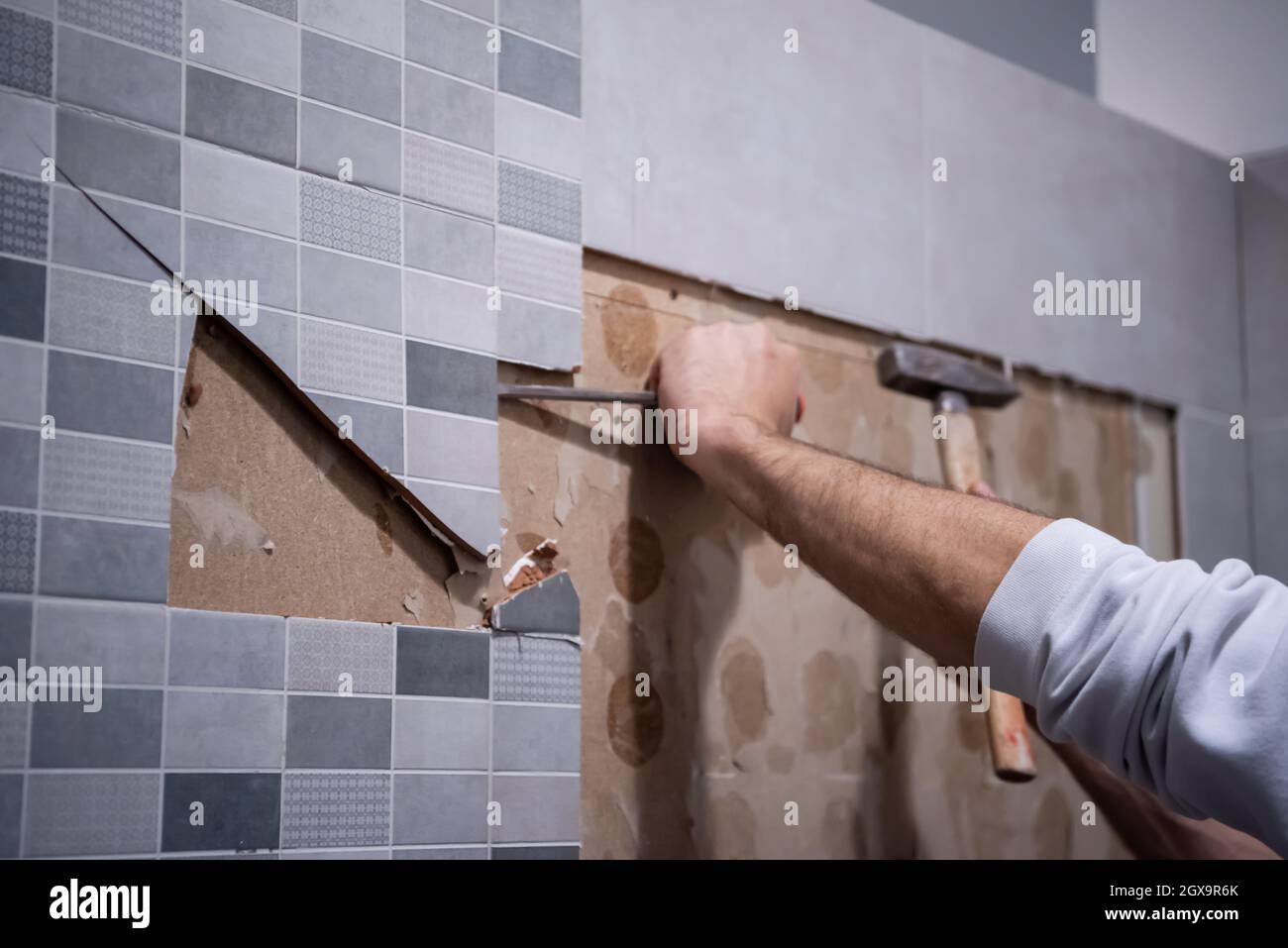 professional worker remove demolish old tiles in a bathroom with hammer ...