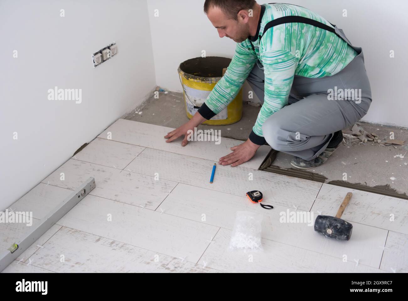 skilled worker installing the ceramic wood effect tiles on the floor ...