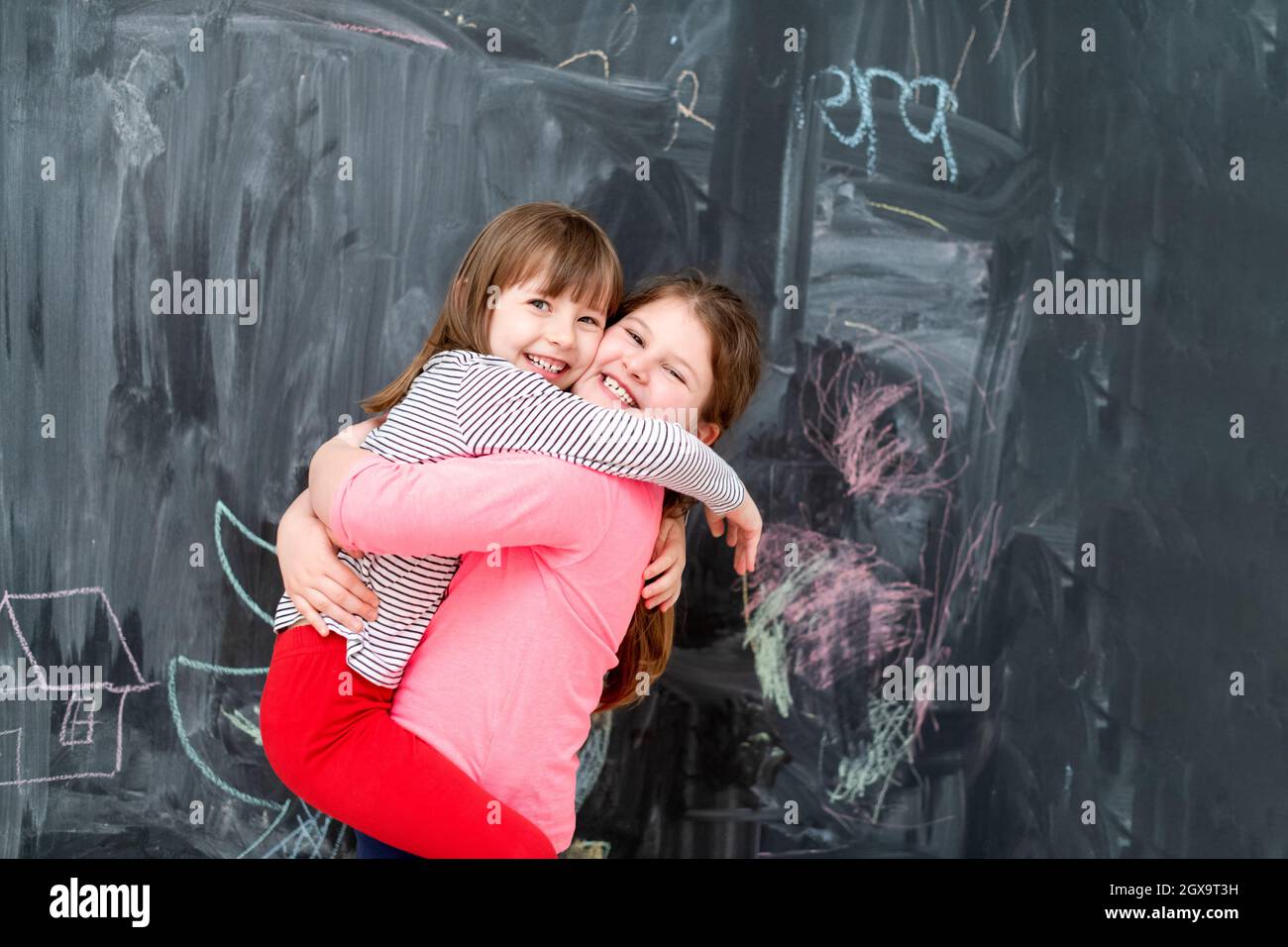portrait of two happy cute little girls hugging each other while having ...