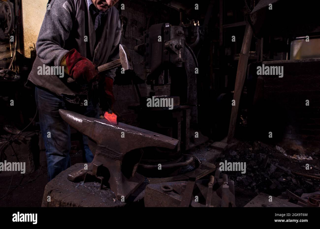 blacksmith manually forging the red hot molten metal on the anvil in ...