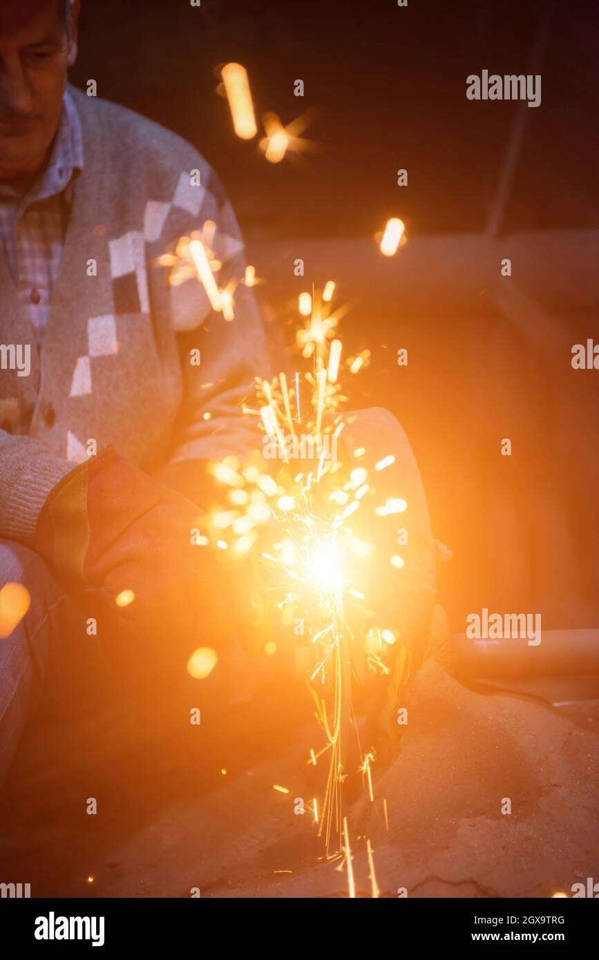 the blacksmith polishing metal products making sparks while using a ...
