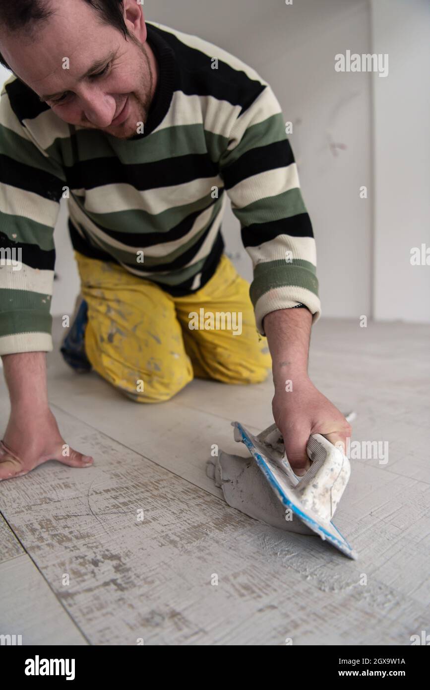 Grouting ceramic tiles. Tilers filling the space between ceramic wood ...